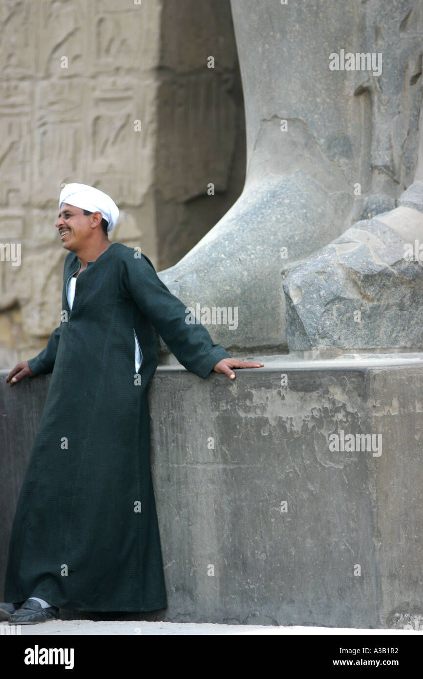 Egyptian keeper by feet of huge statue of pharaoh in Luxor Temple ...