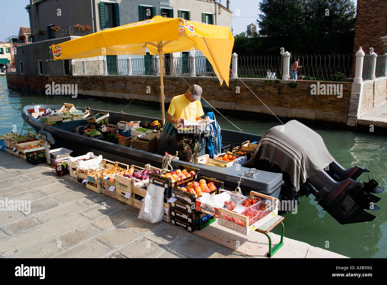 ITALY Veneto Venice A fruit and vegetable vendor in his boat moored alongside the Fondamenta dei ...