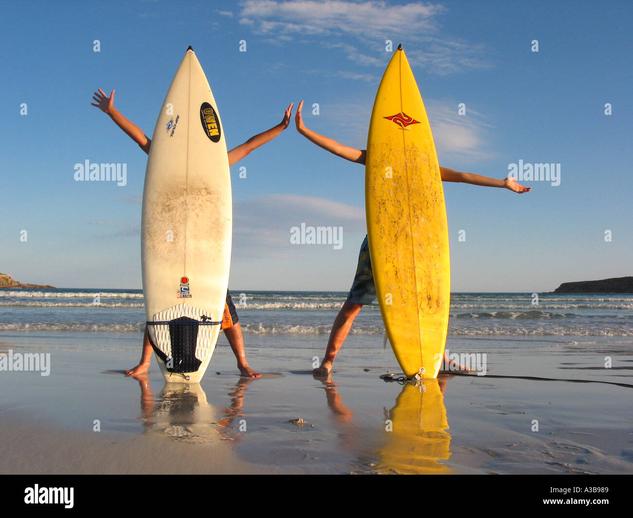 X Generation two surf boards on beach with teenagers fooling about ...