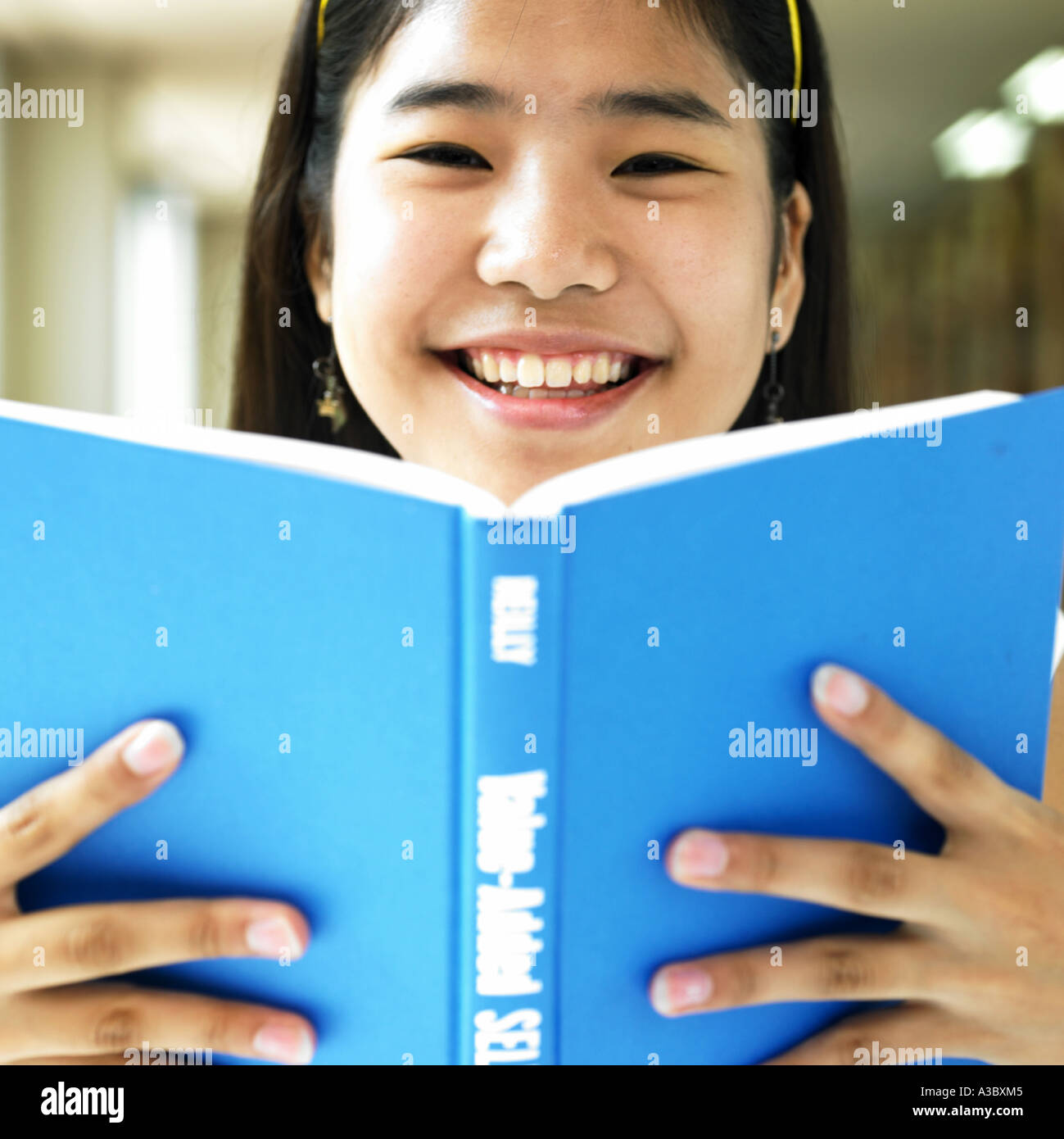 a girl reading a blue book is smiling Stock Photo - Alamy