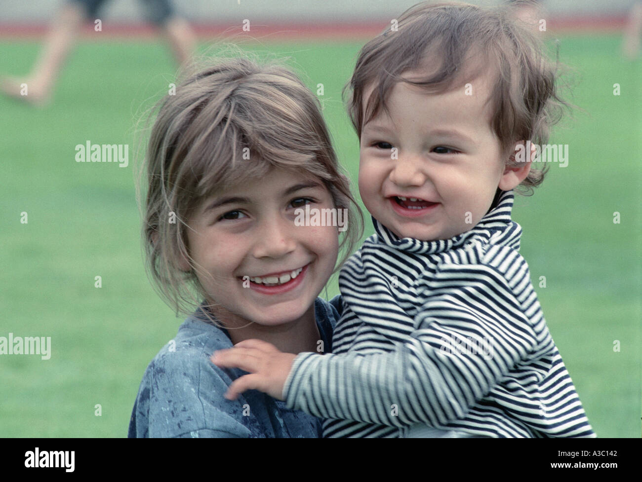 Girl carrying her little cousin Stock Photo - Alamy