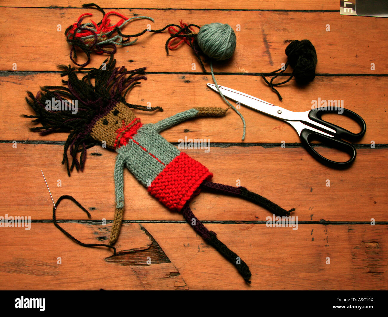 A handmade knitted wool doll with the materials required to make it ...