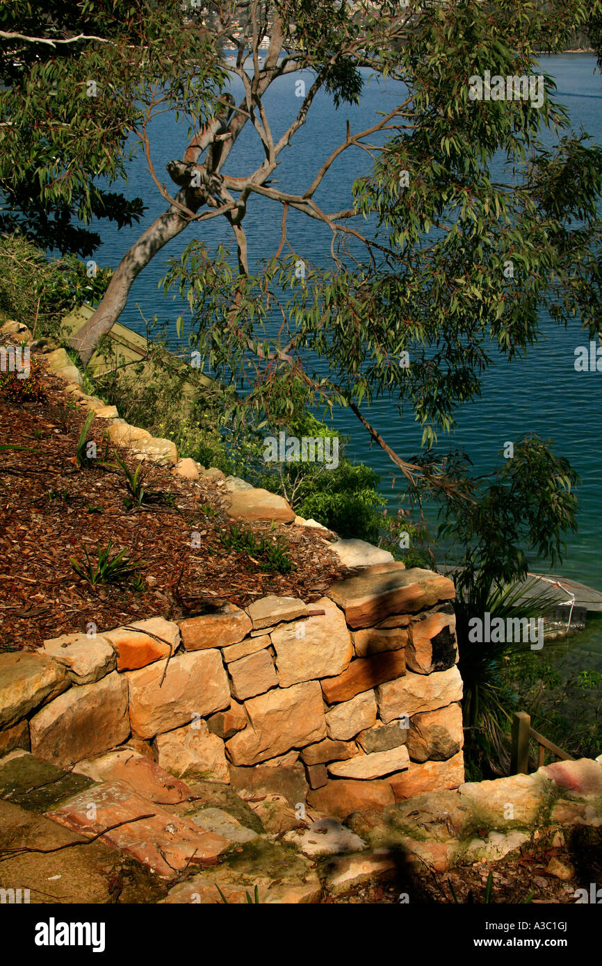 A rough sandstone wall with eucalyptus trees and harbour below in ...