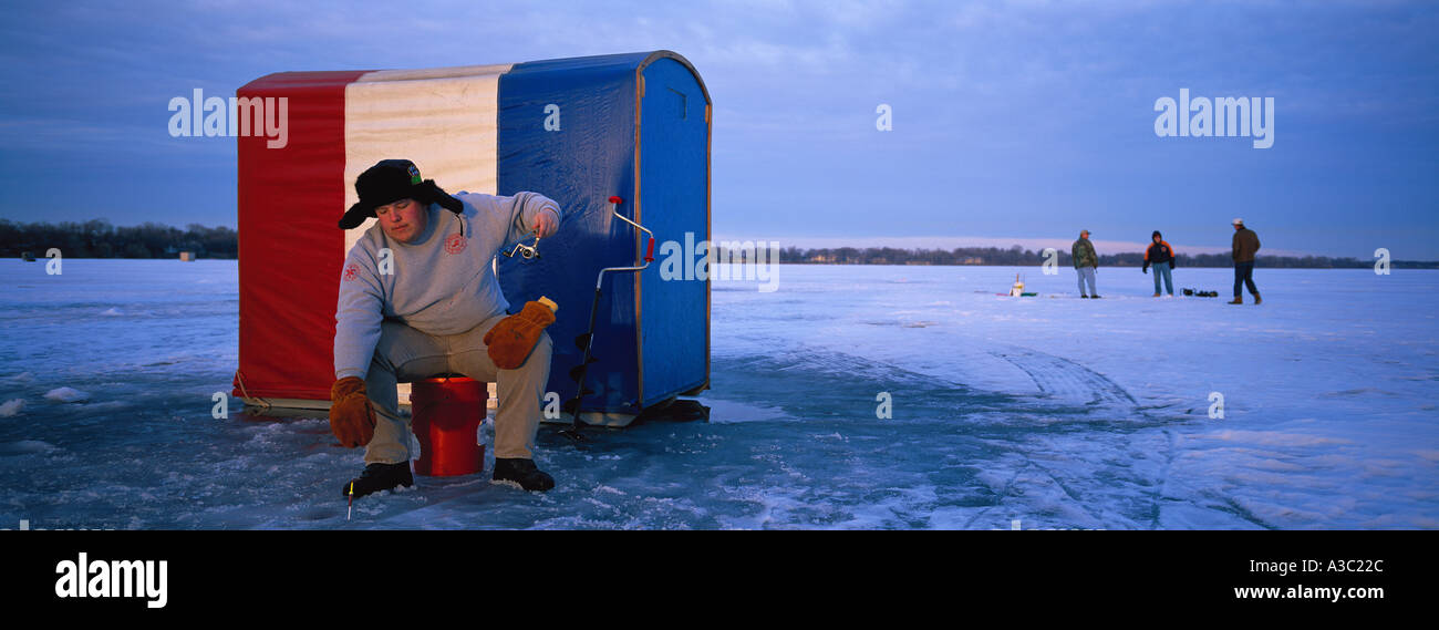 Ice fisherman reeling in line on frozen lake St Paul MN Red white and ...