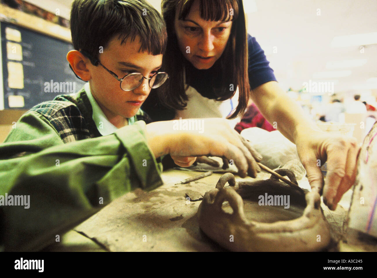A teacher and her fifth grade student working together on a ceramics ...