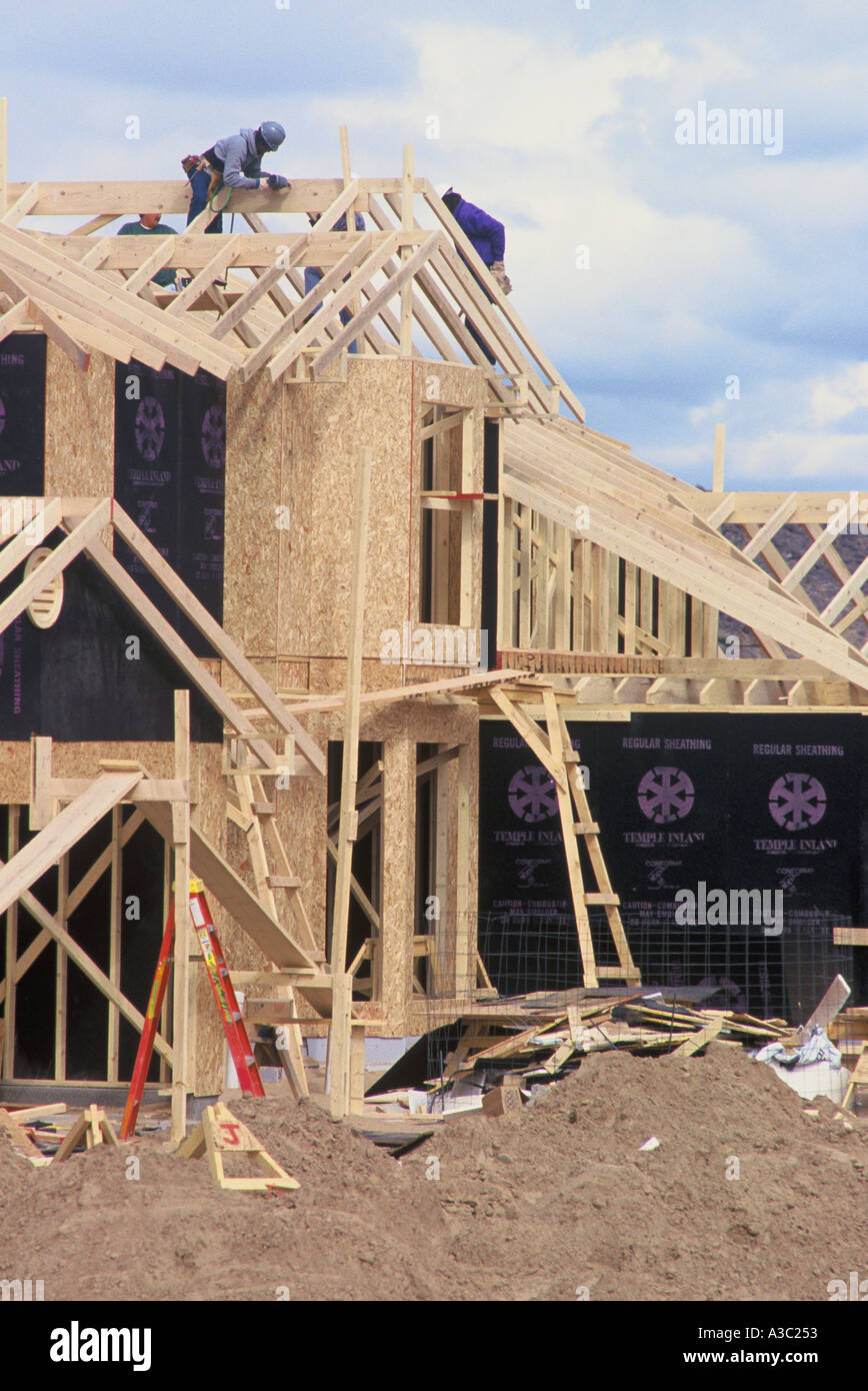 Two construction workers on the unfinished roof of a residential house ...