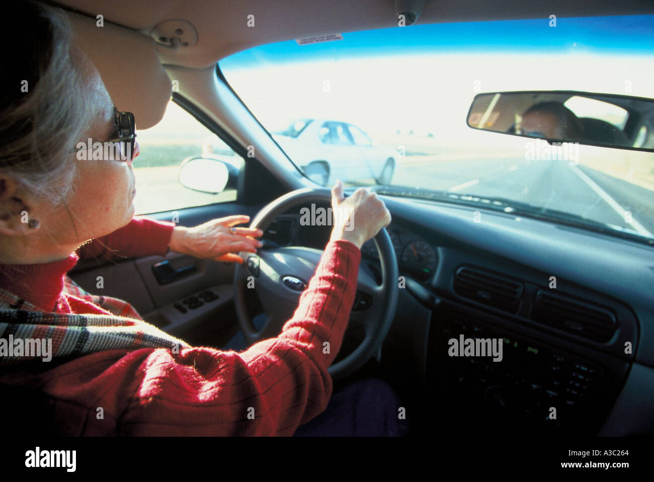 Side view of a female driver taken inside the car while driving along ...