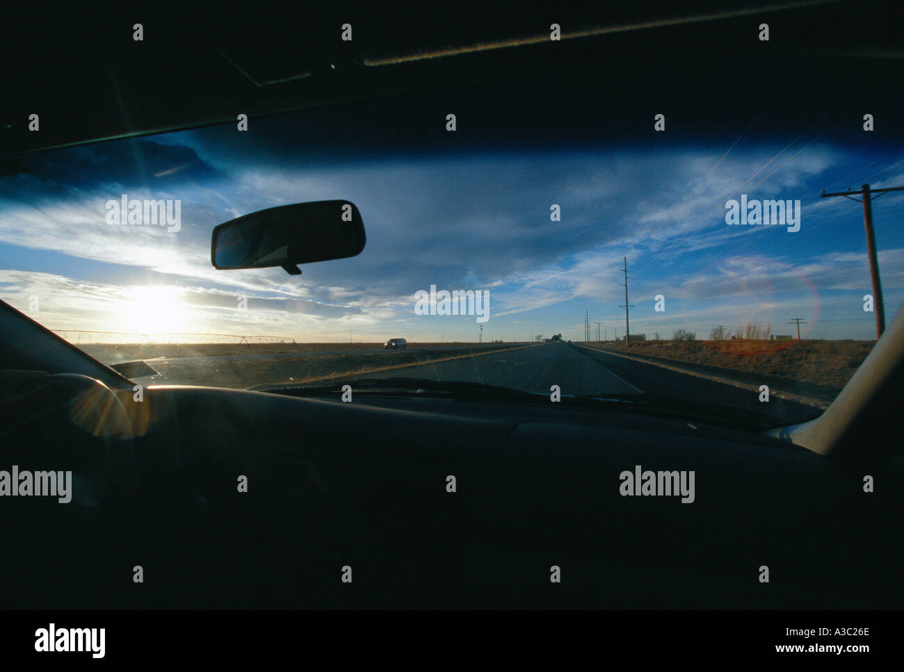 View of the sunset as seen through the front window of a car while ...