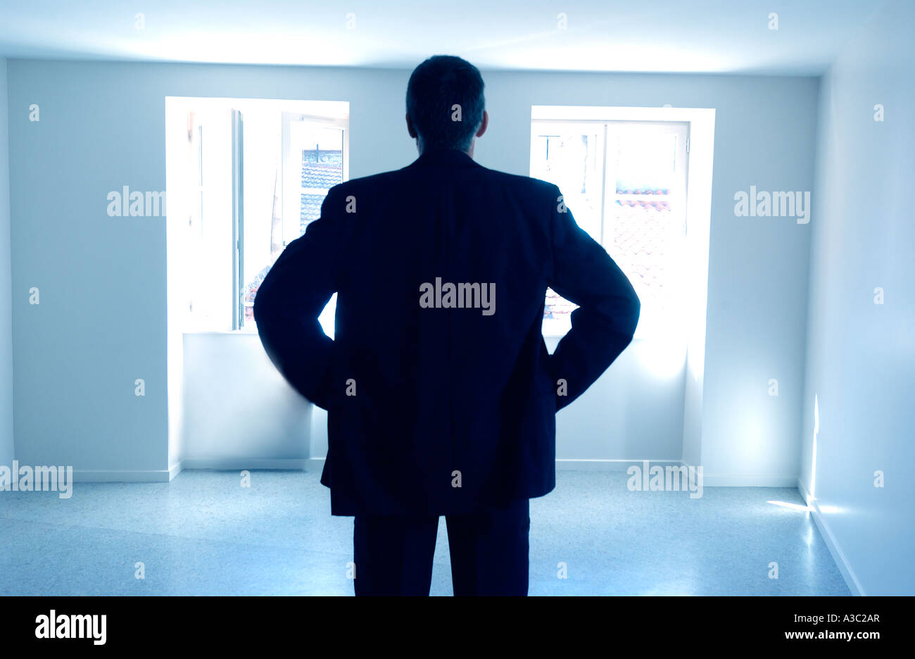 Man standing in an empty room / apartment / house - rear view ...