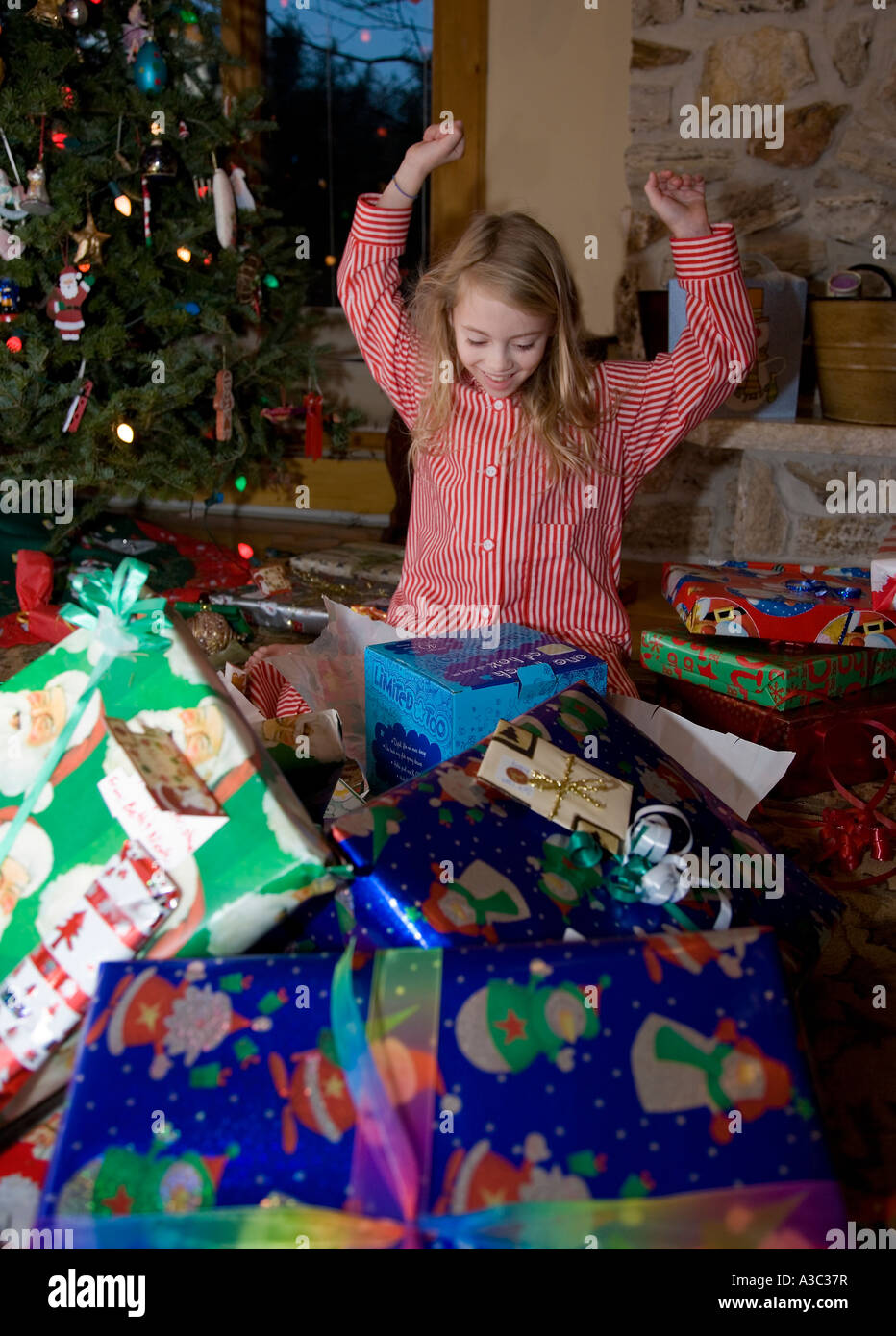 Child opening a gift under a Christmas tree Stock Photo - Alamy