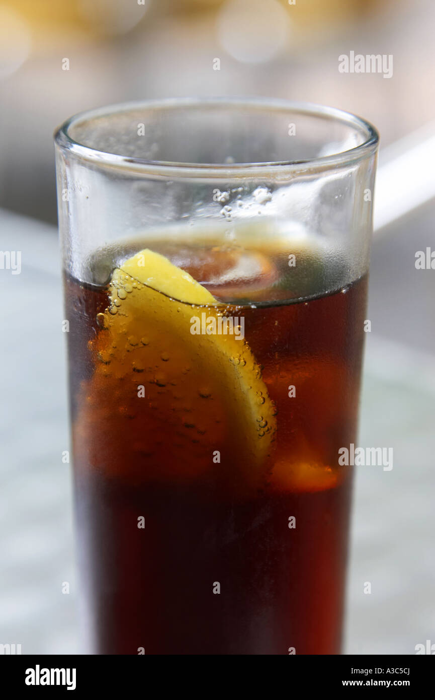 close up of tall glass of cola with a slice of lemon on an outdoor cafe ...