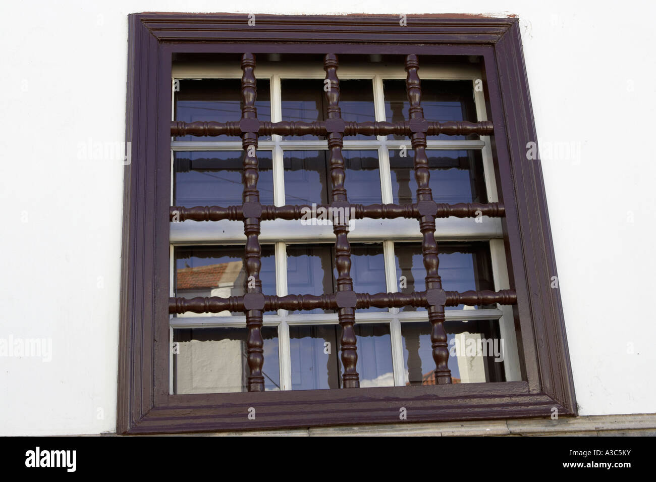 brown wooden security bars in front of wood and glass window of a house ...