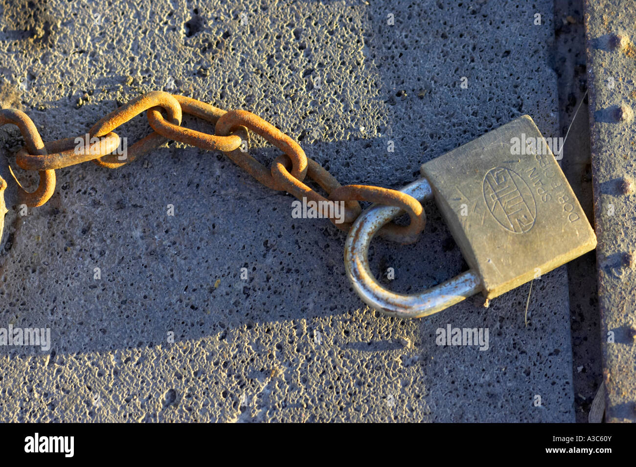 spanish brass padlock attached to rusty chain lying on concrete in ...