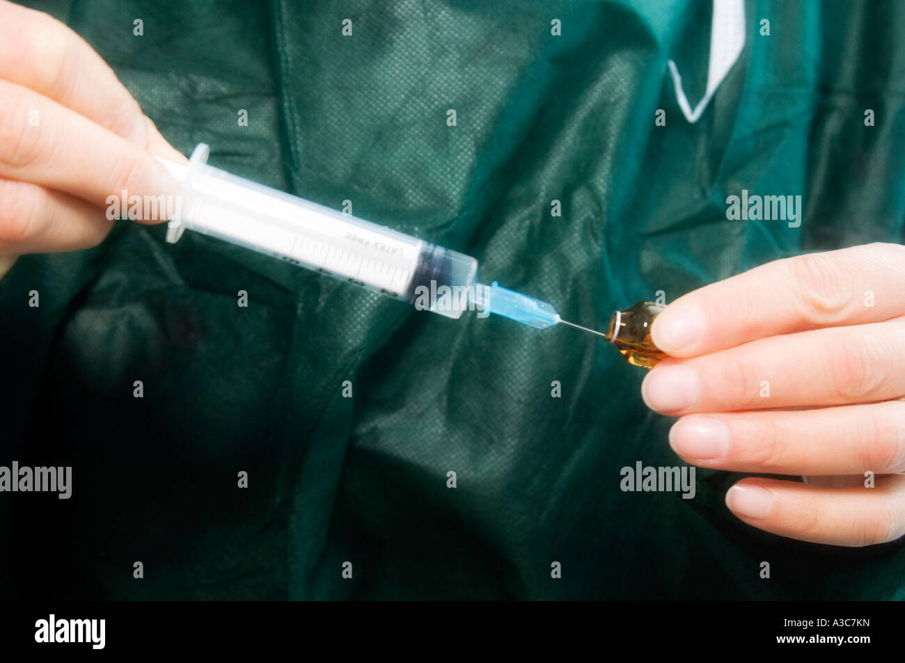Close up of the hands of a doctor with hypodermic syringe and phial ...