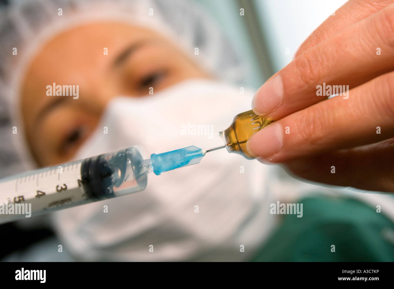 Close up of the hands of a nurse with hypodermic syringe and phial ...