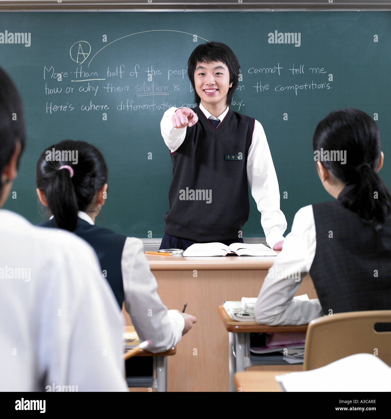 A student in front of the class pointing at another student Stock Photo ...