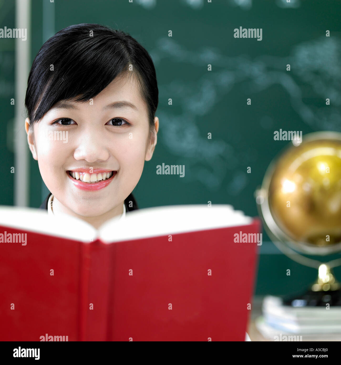 A student reading a book beside a globe Stock Photo - Alamy