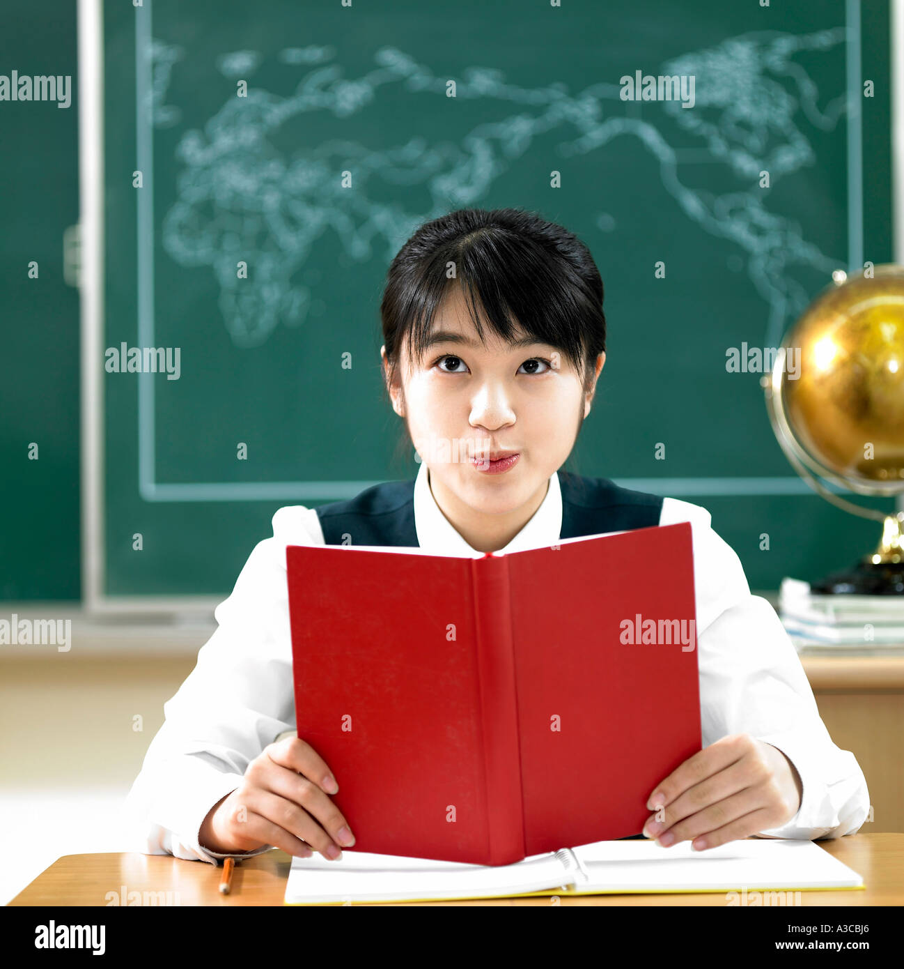 A student reading a book beside a globe Stock Photo - Alamy