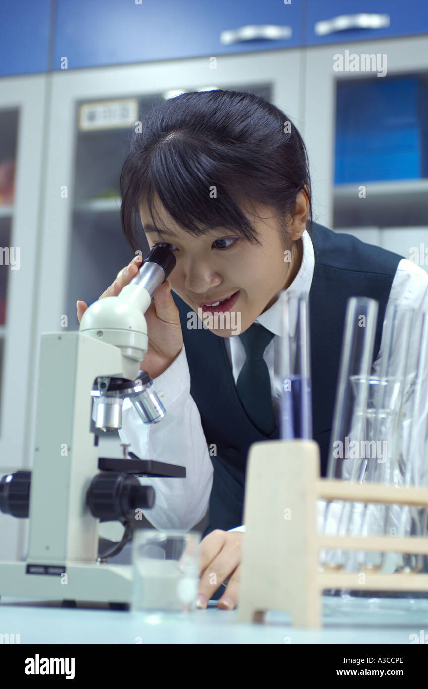a girl in a school uniform is observing through the microscope Stock ...