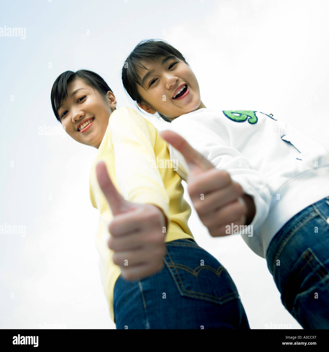 Two teenage girls showing their thumbs up Stock Photo - Alamy