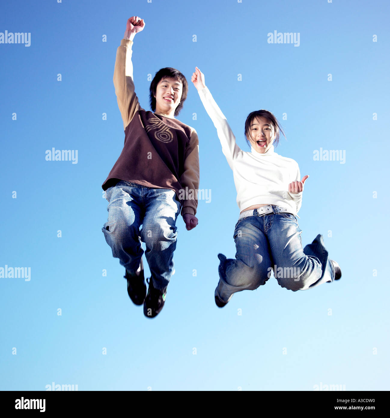 A teenage girl and boy jumping in the air Stock Photo - Alamy
