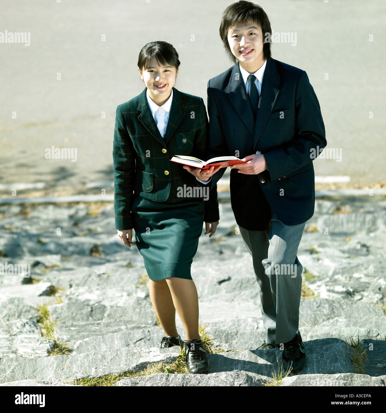 A male student with a red book and a female student are standing on a ...