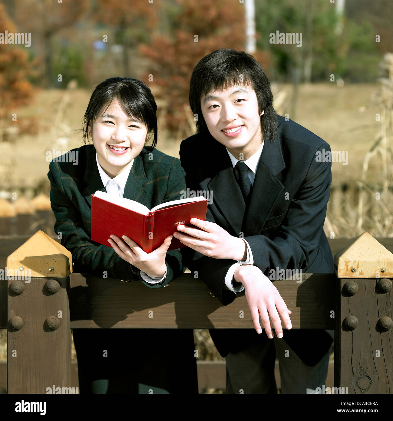 Two teenagers in a school uniform are holding a book and smiling Stock ...