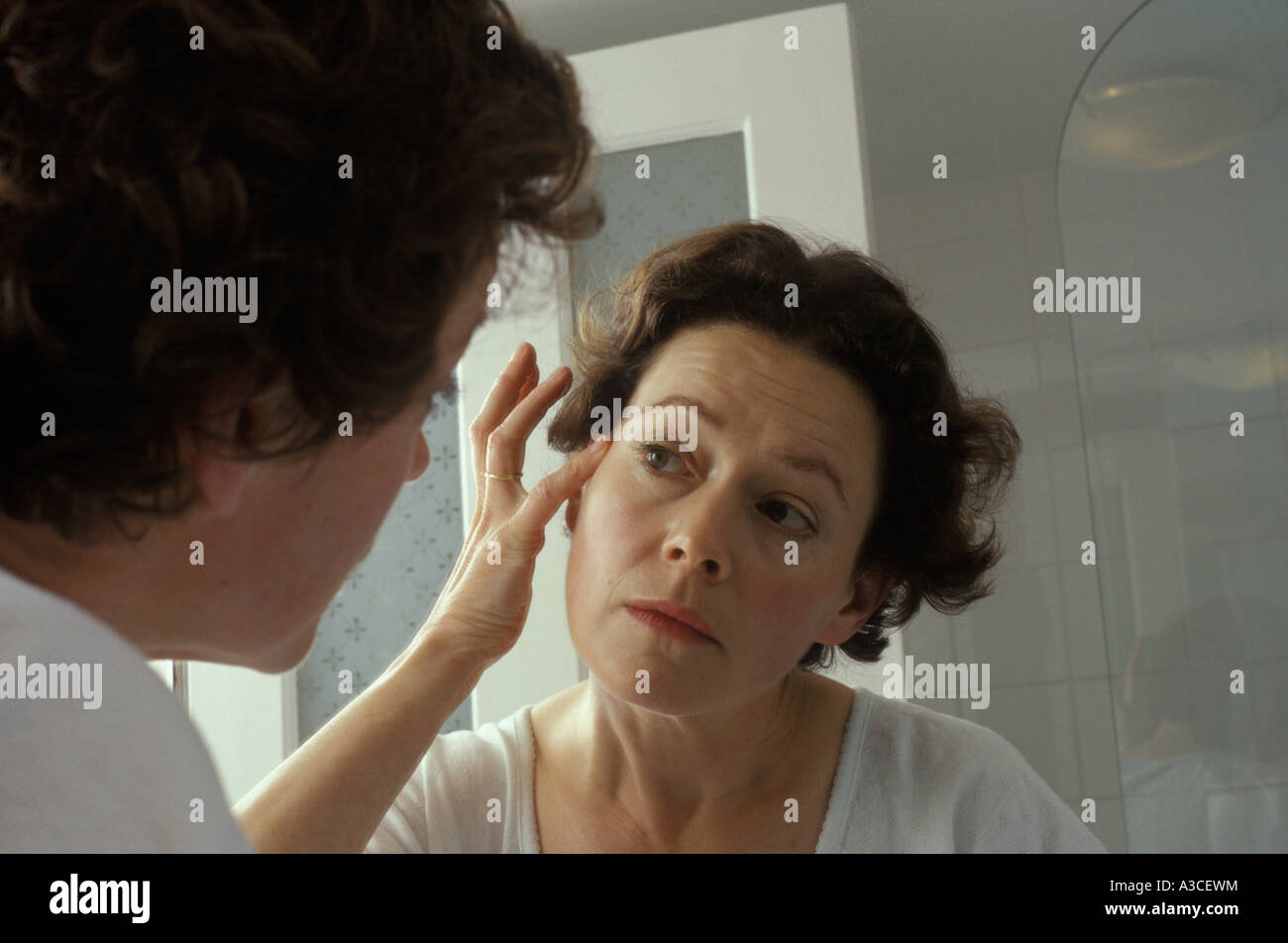 middle aged woman looking at her wrinkles in the mirror Stock Photo - Alamy