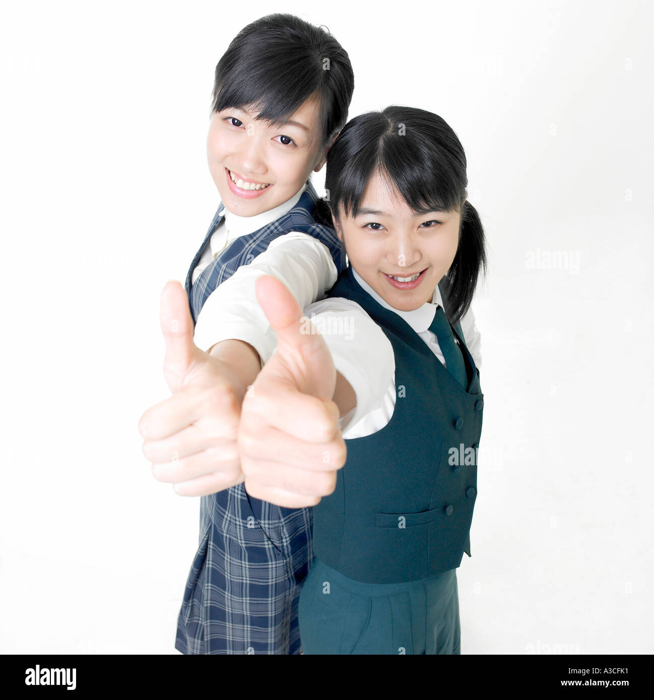 Two female students in different school uniforms are putting their ...