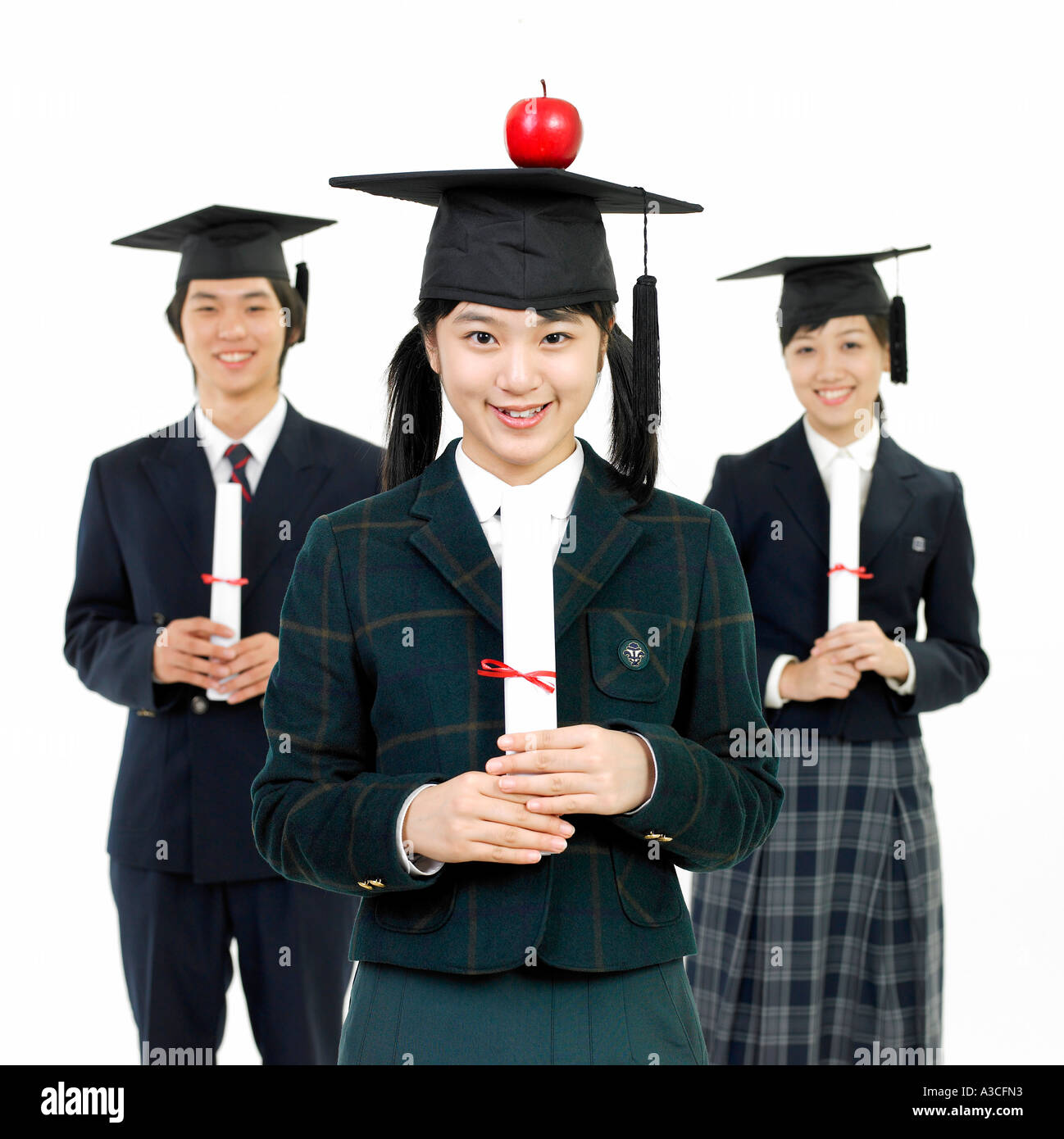 Three students are holding their diplomas with graduation caps and ...