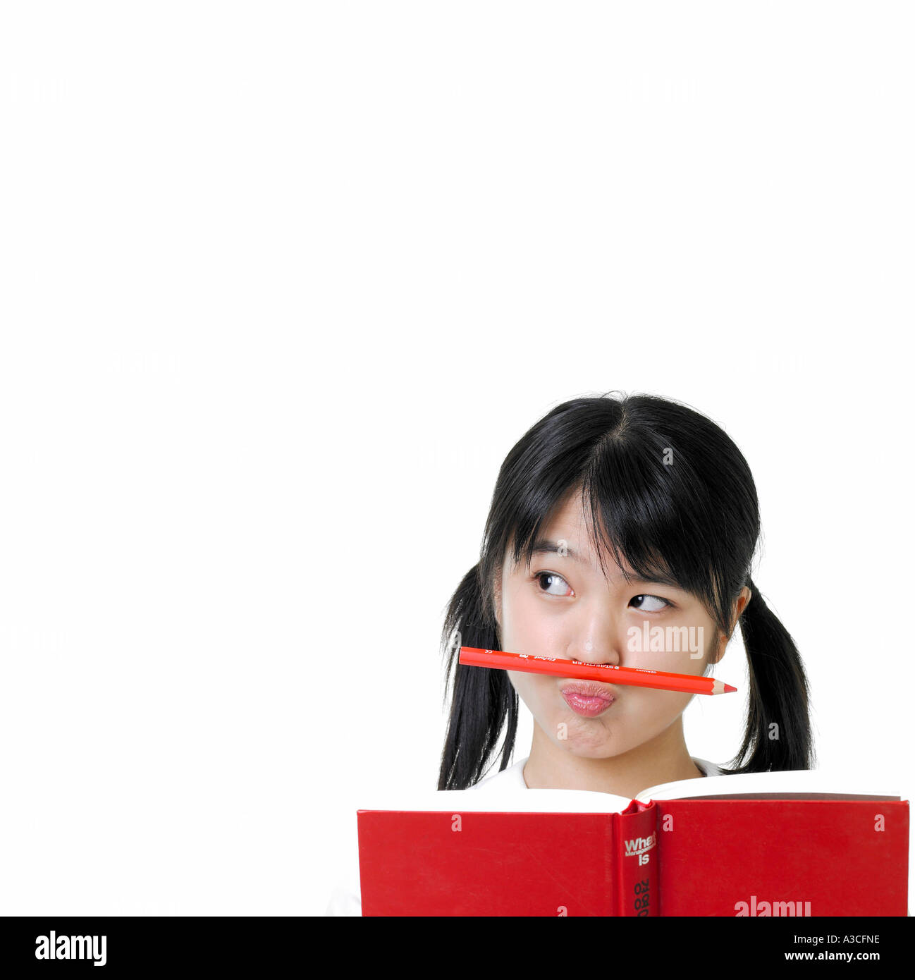 A girl with a pencil on her lips is holding a red book Stock Photo - Alamy