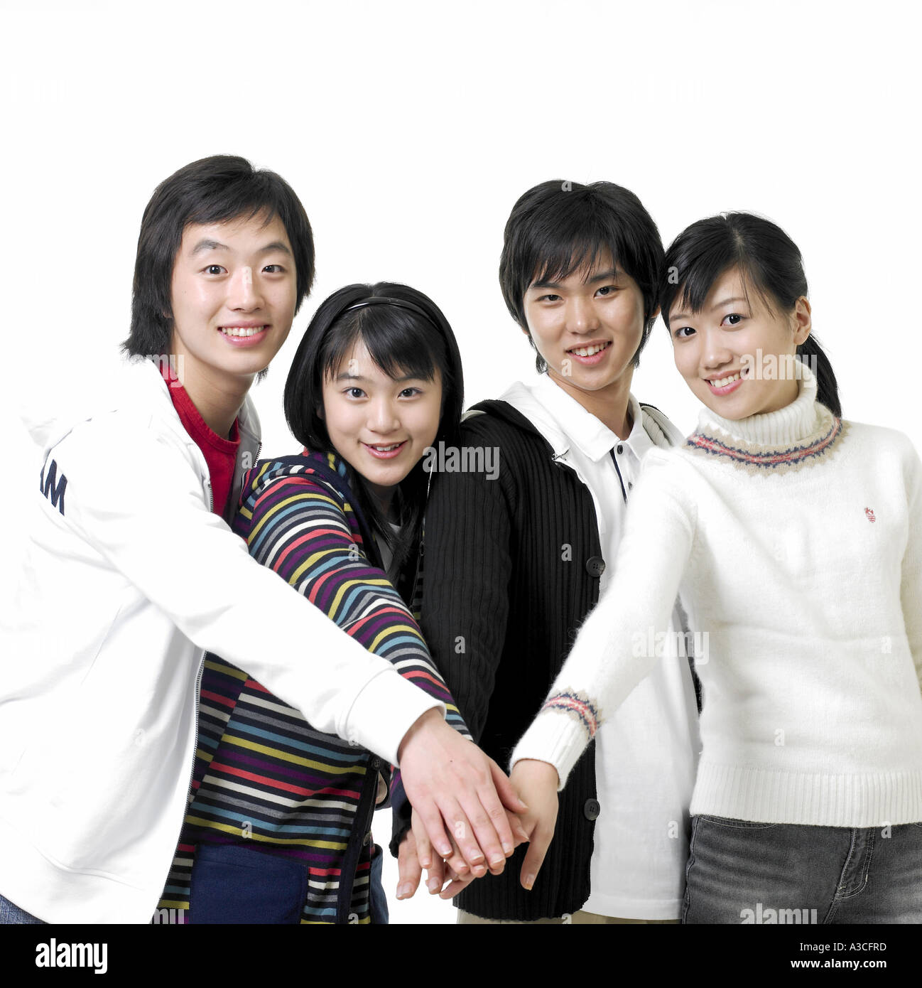 Four students are putting their hands down together Stock Photo - Alamy