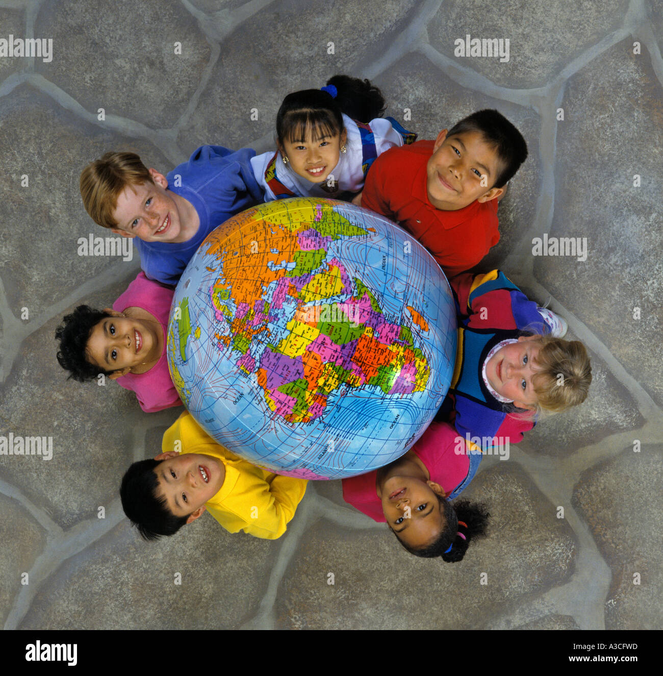 Third grade group of multi-ethnic children holding up globe of planet ...