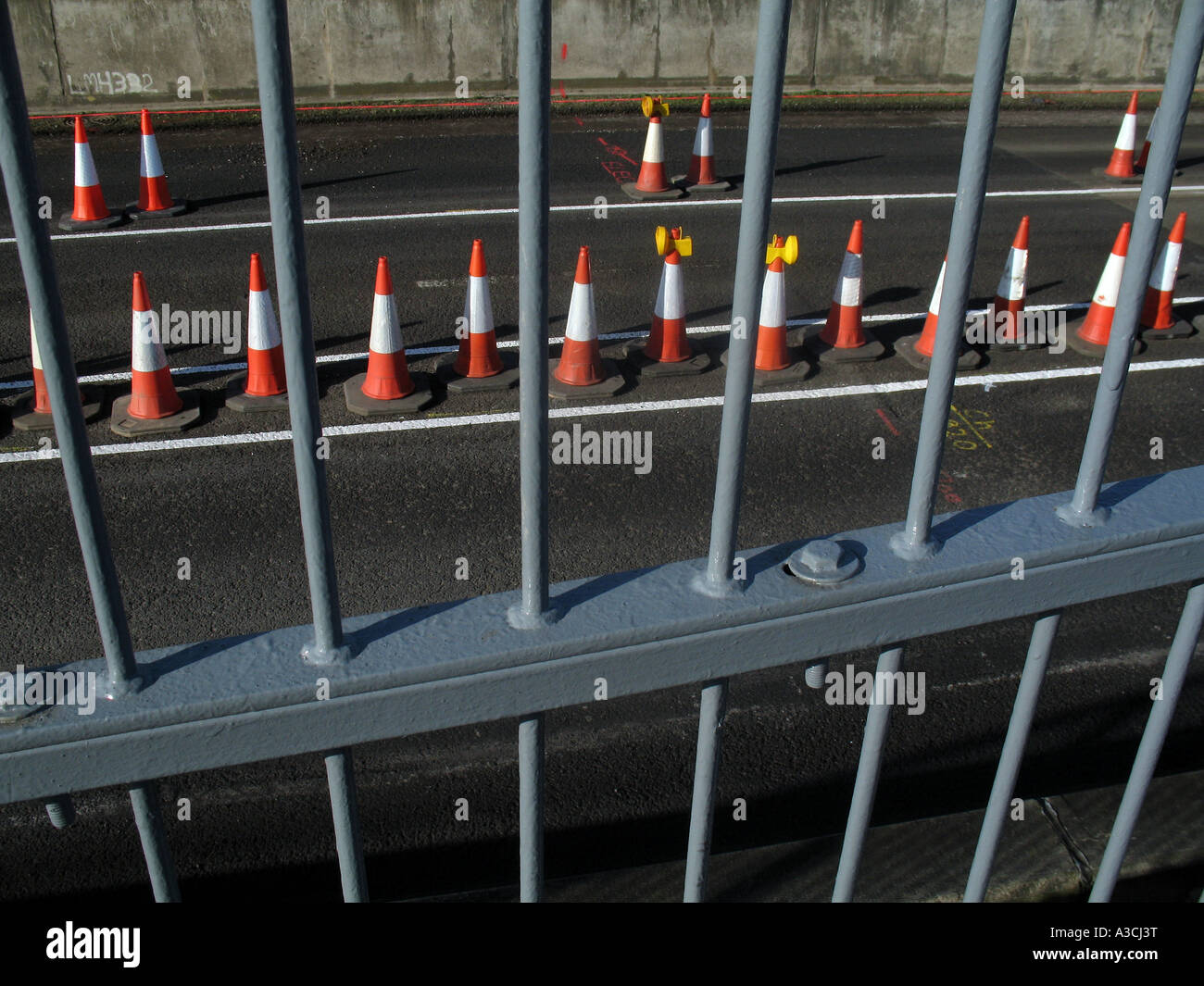 Traffic cones on duel carriageway seen through pedestrian safety fence ...