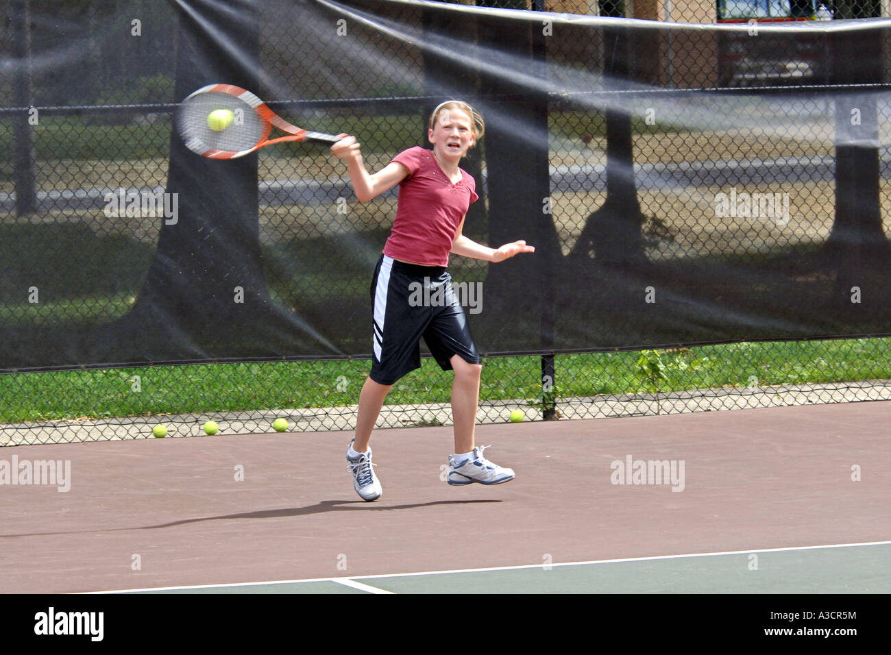 Teenage girl practises her tennis skills at a after-school training ...