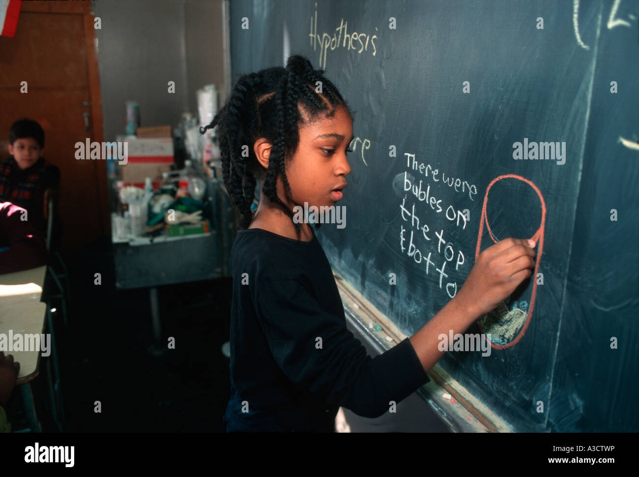 Elementary school student works at the chalkboard in science class ...