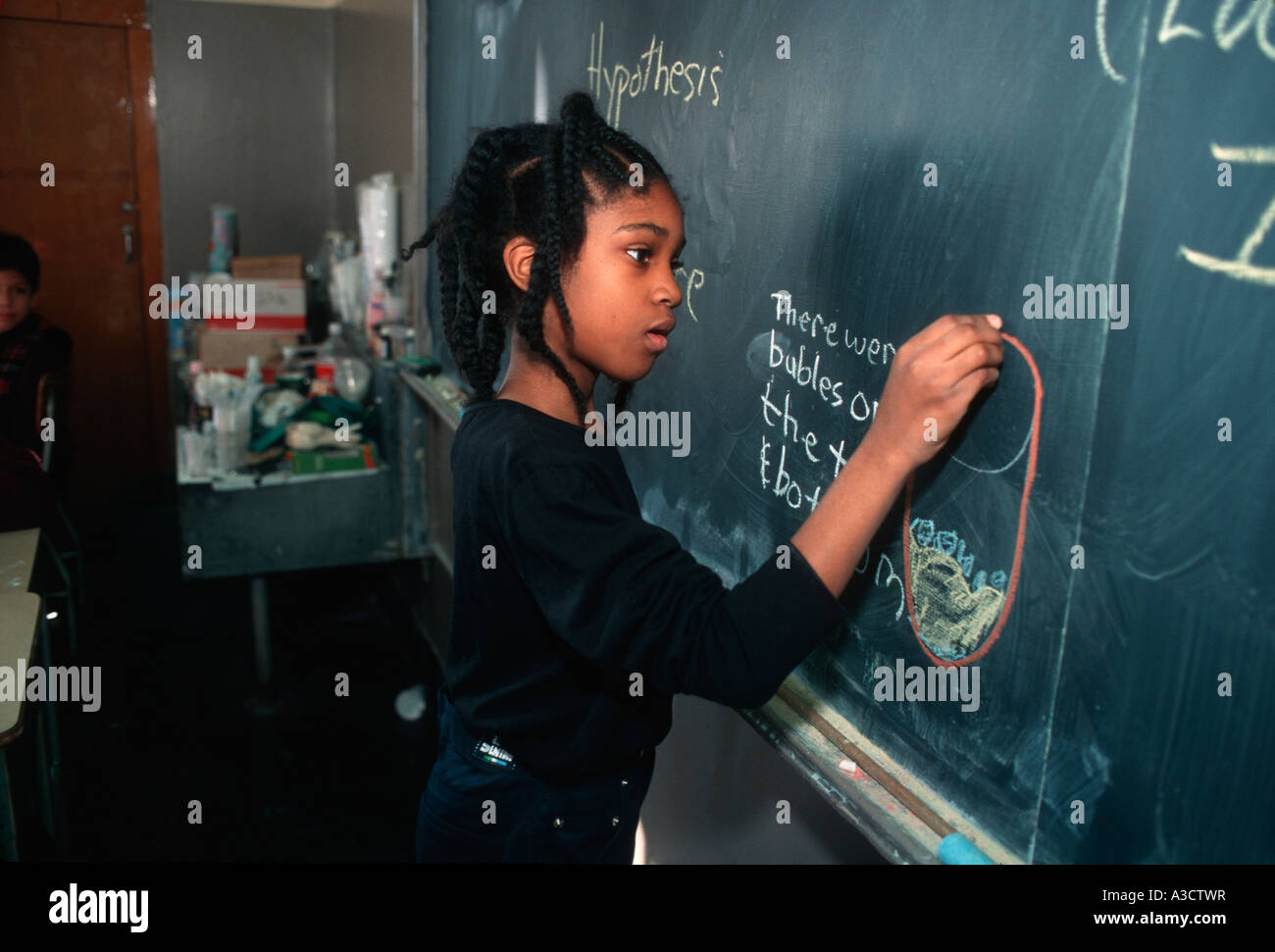 Elementary school student works at the chalkboard in science class ...