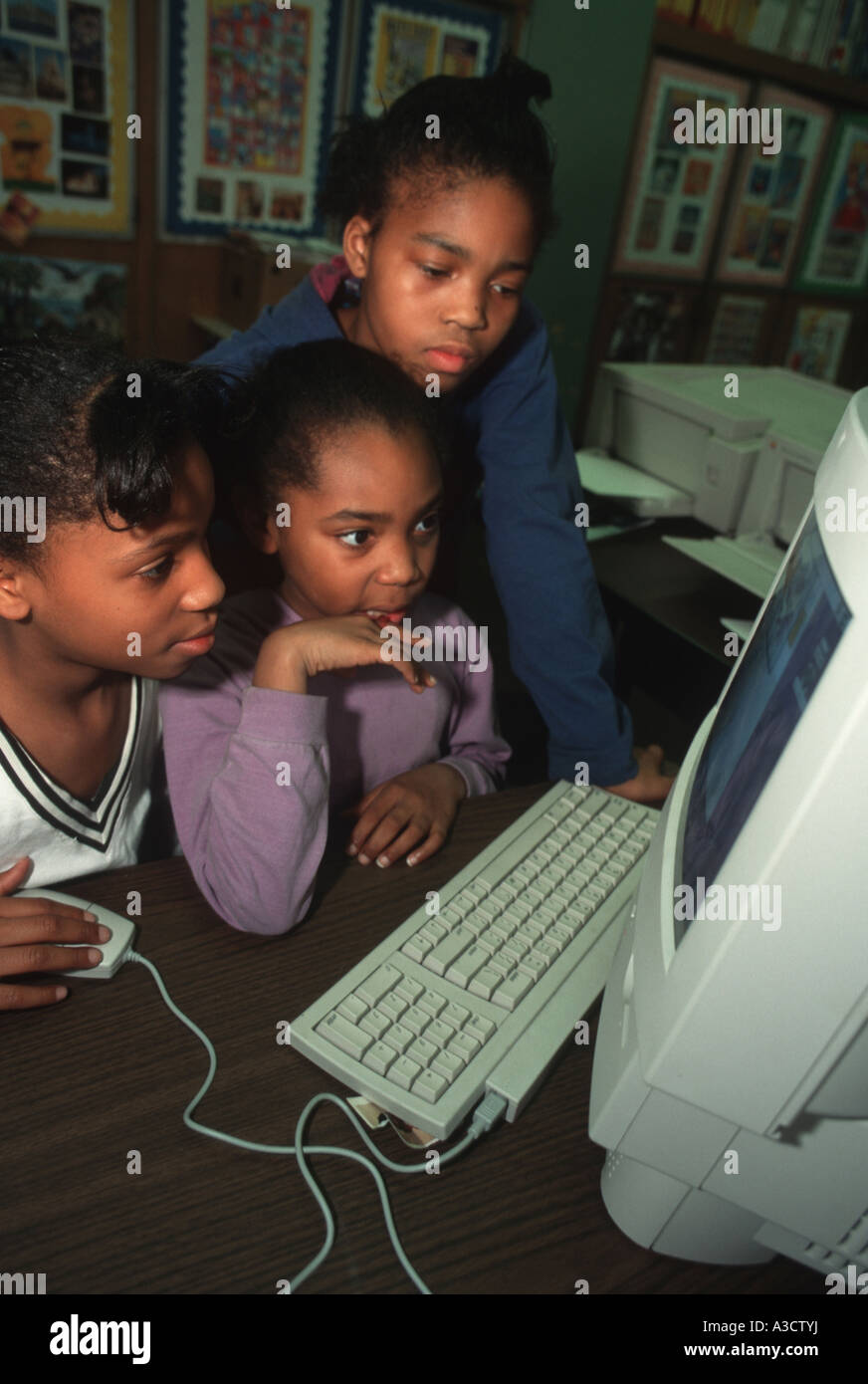 Girls work at a computer together at an inner city public school in ...