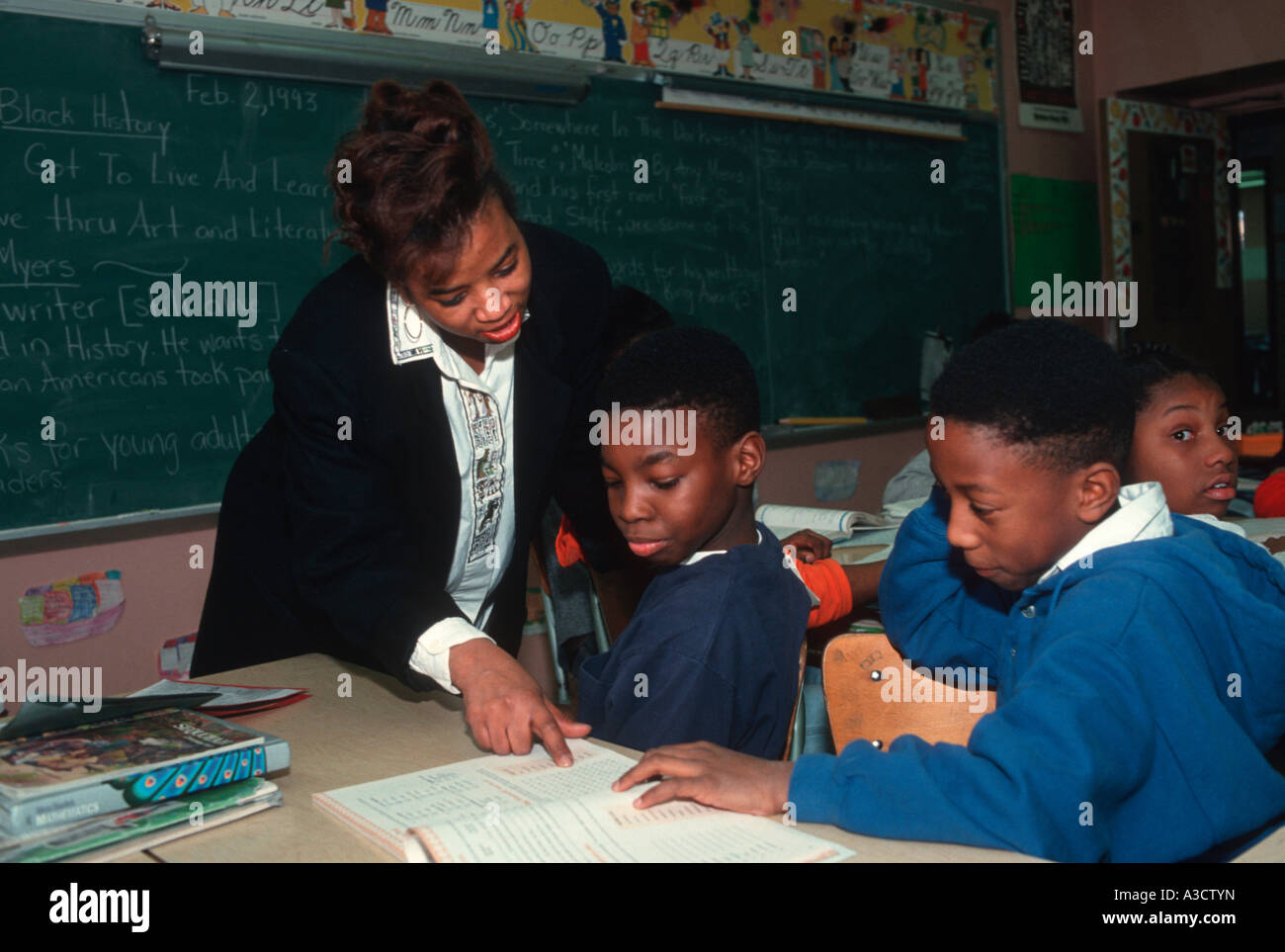 Teacher assists student with class work at an elementary school in ...
