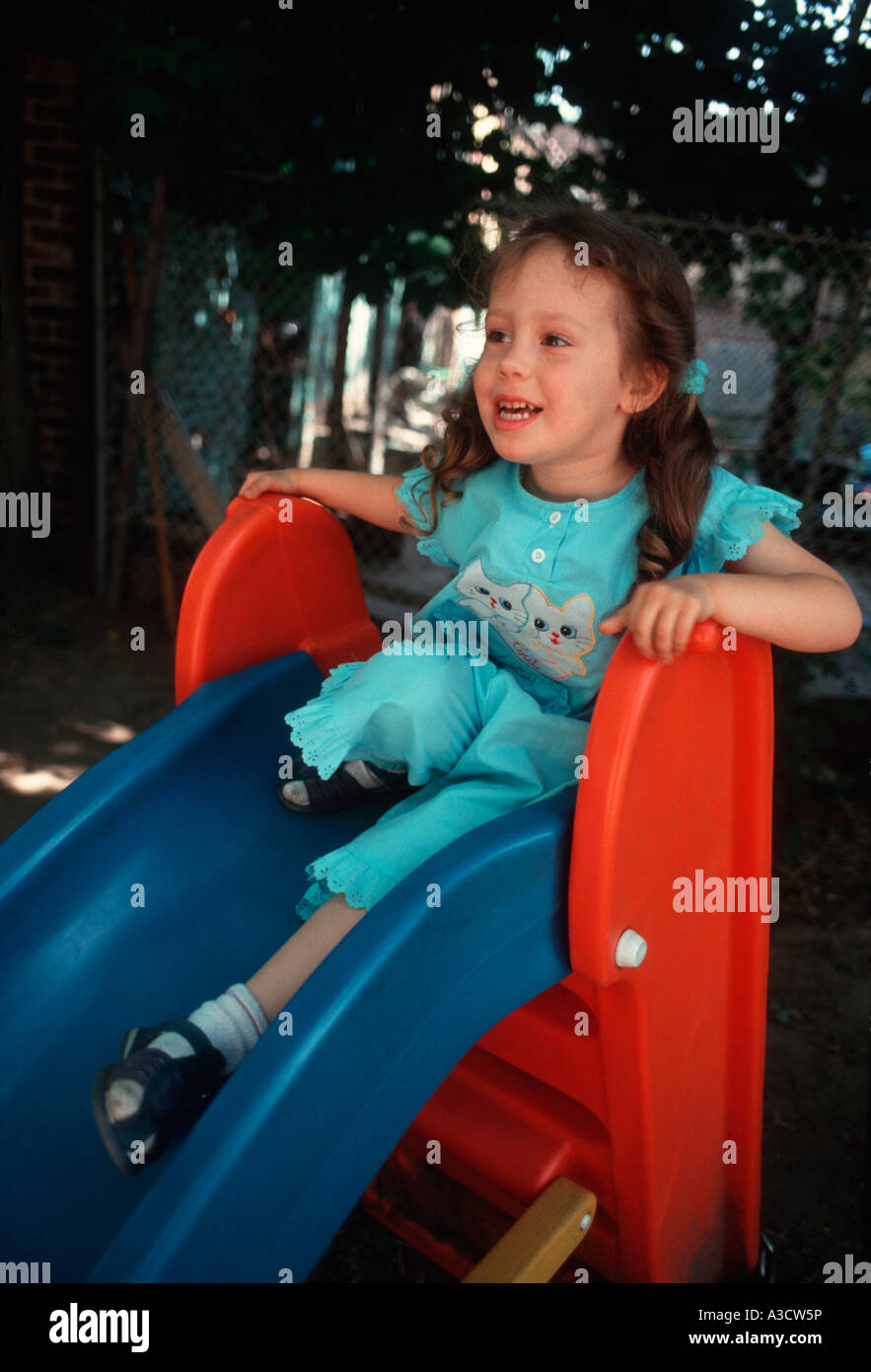 Child gets ready to slide down the slide on the playground at nursery ...