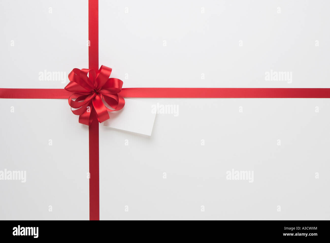 large gift wrapped in white with red ribbon and blank gift tag Stock ...