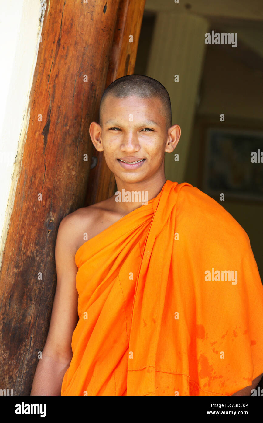 Close up portrait of young Buddhist monk in traditional orange robes ...