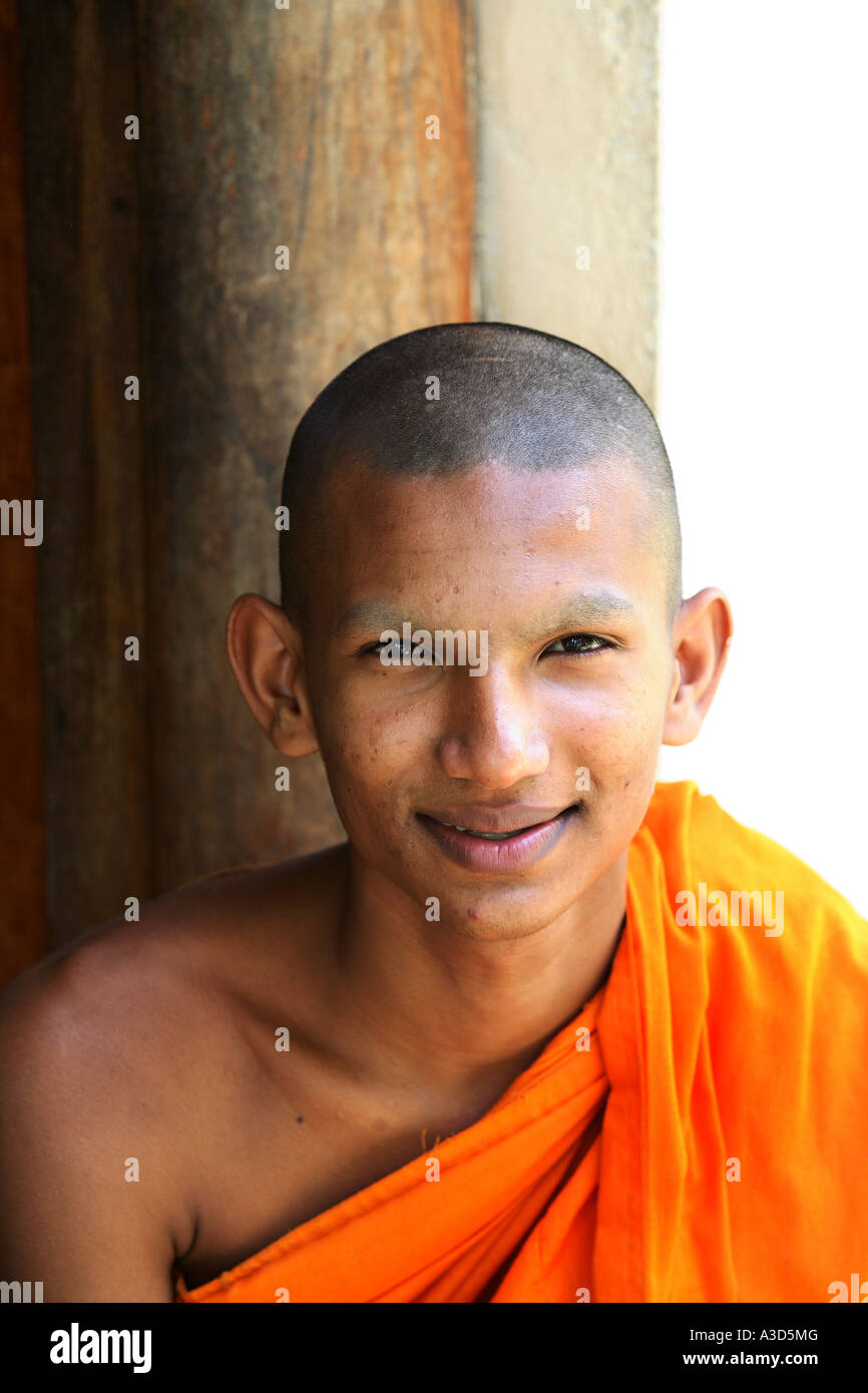 Close up portrait of young Buddhist monk in traditional orange robes ...
