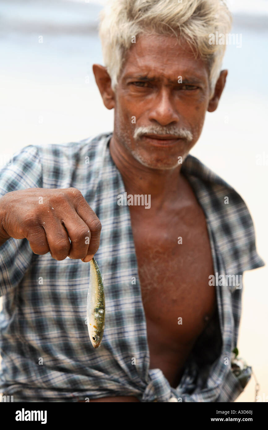 Environmental portrait of elderly man with fish caught from pole in sea ...