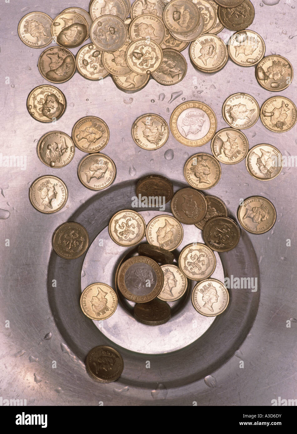 Money down the drain concept image showing pound sterling coins being ...