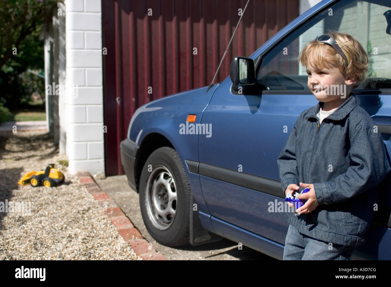 Little boy leaning against car in sunshine Stock Photo - Alamy