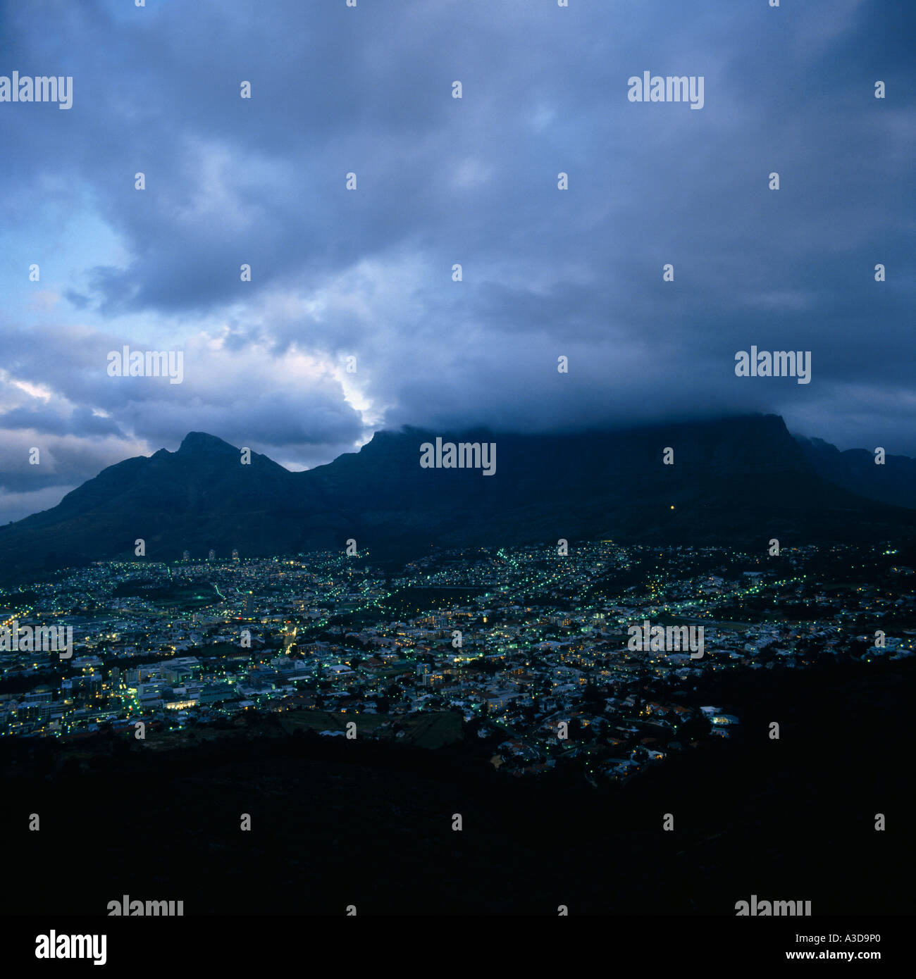 View over the city of Cape Town lit up after dusk and low rain clouds ...