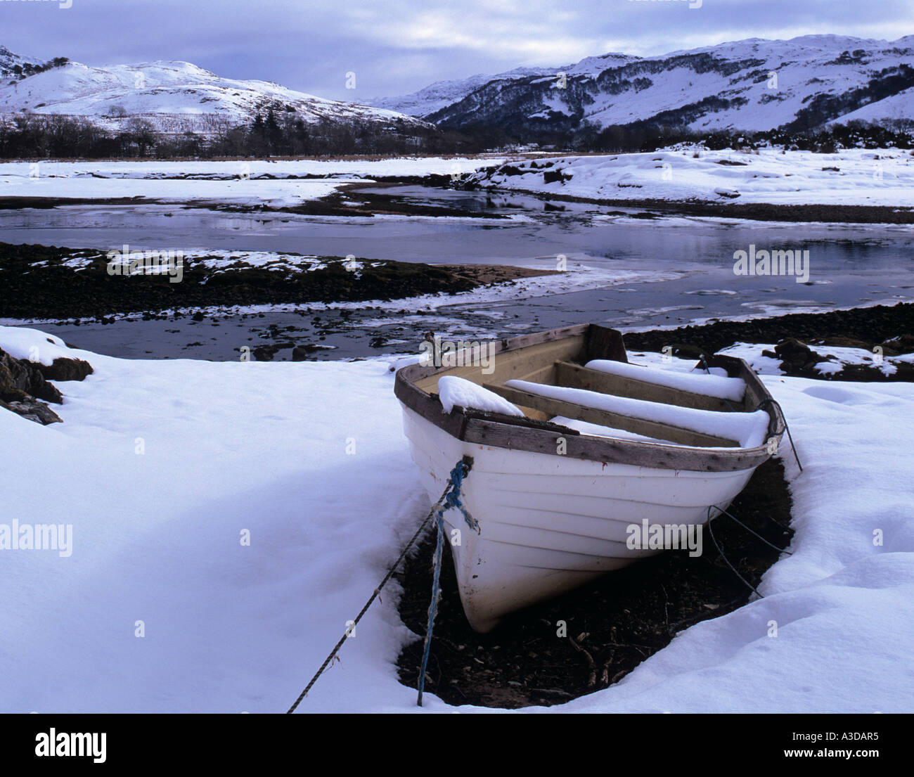 Wooden boat by the Glenmore River estuary in Galltair with snow on ...