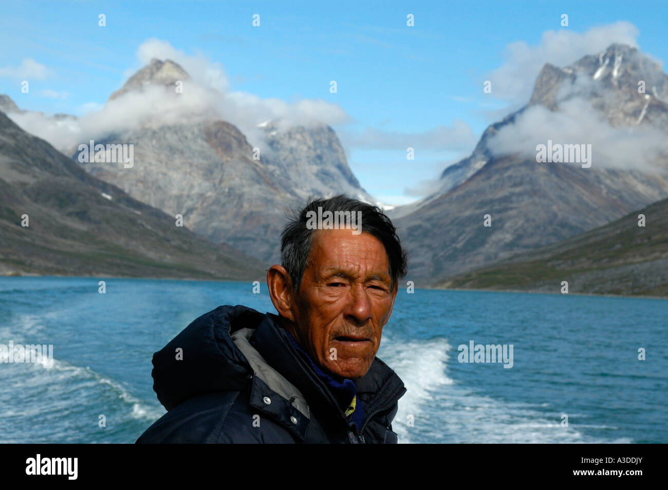 Portrait Inuit Greenlander in Qinngertivaq Fjord with high mountains ...