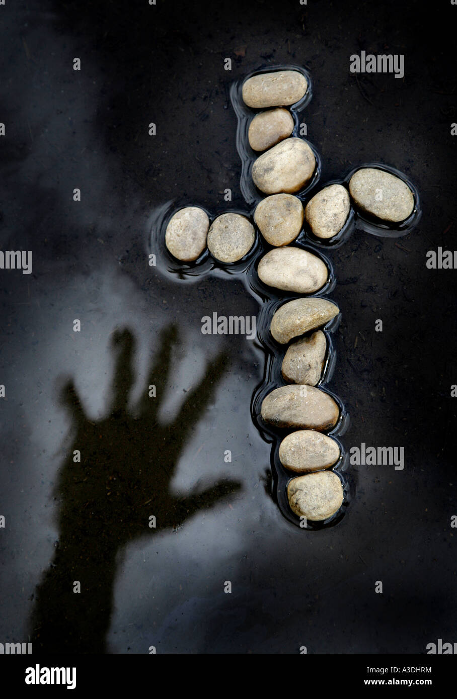 Hand reaching over water for cross made of rocks Stock Photo - Alamy
